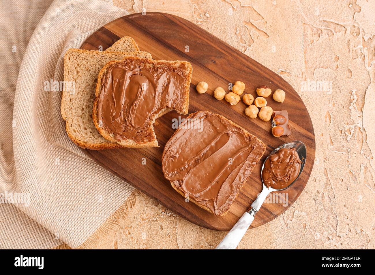 Wooden board of tasty toasts with hazelnut butter and nuts on color ...