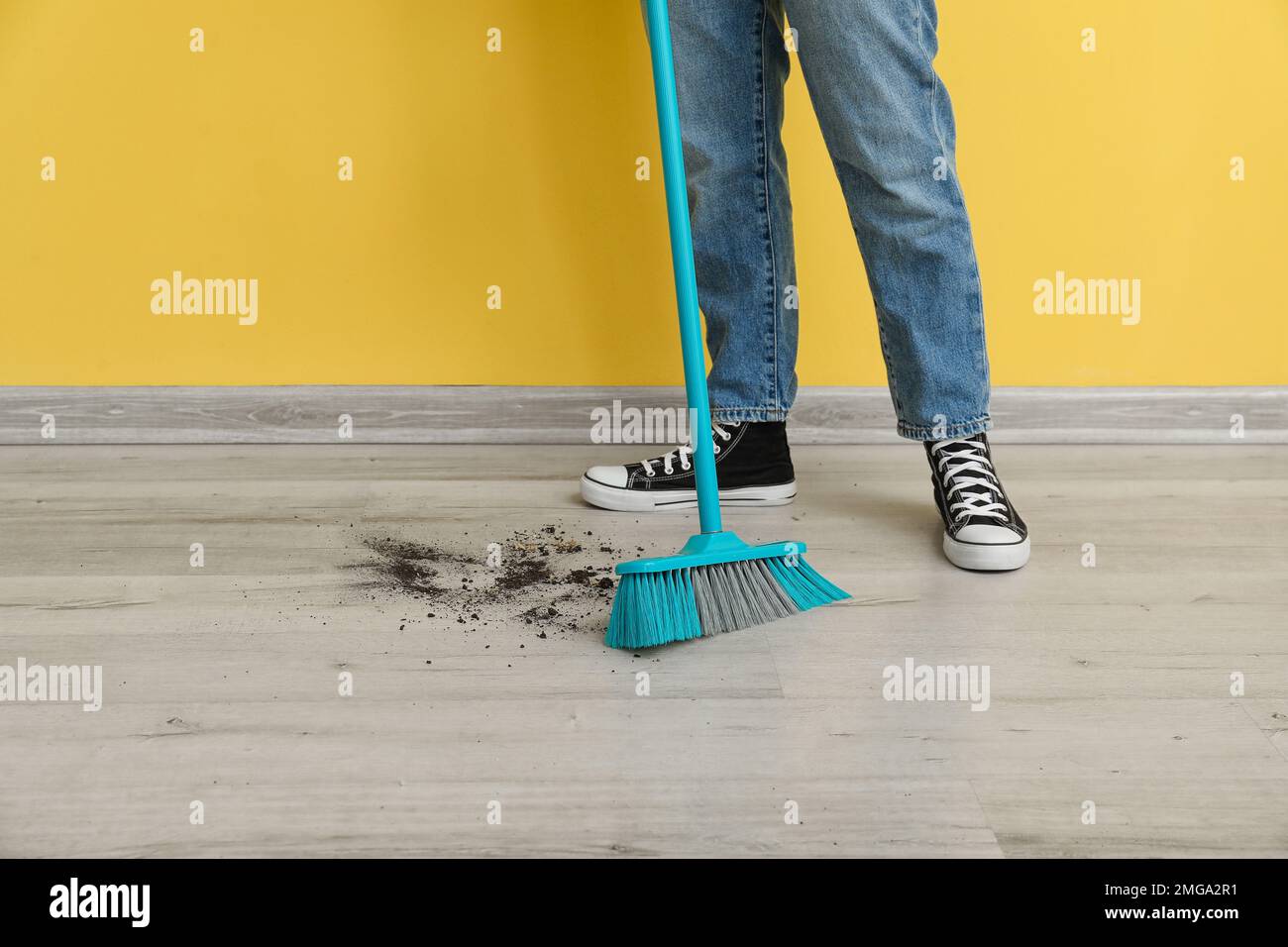 Woman sweeping rubbish with broom Stock Photo - Alamy