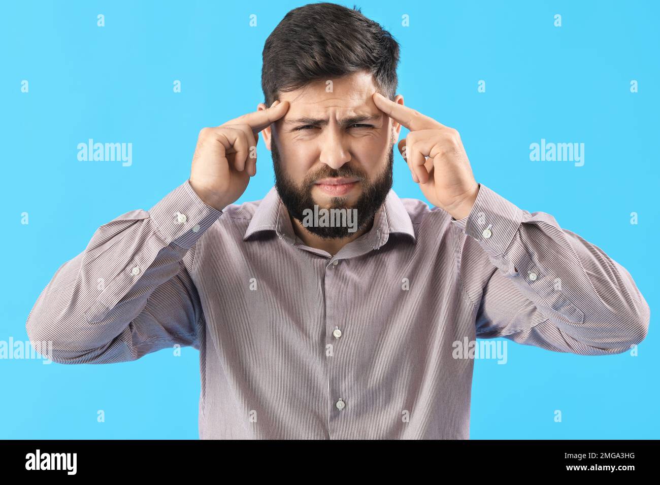 Young man suffering from loud noise on blue background Stock Photo - Alamy