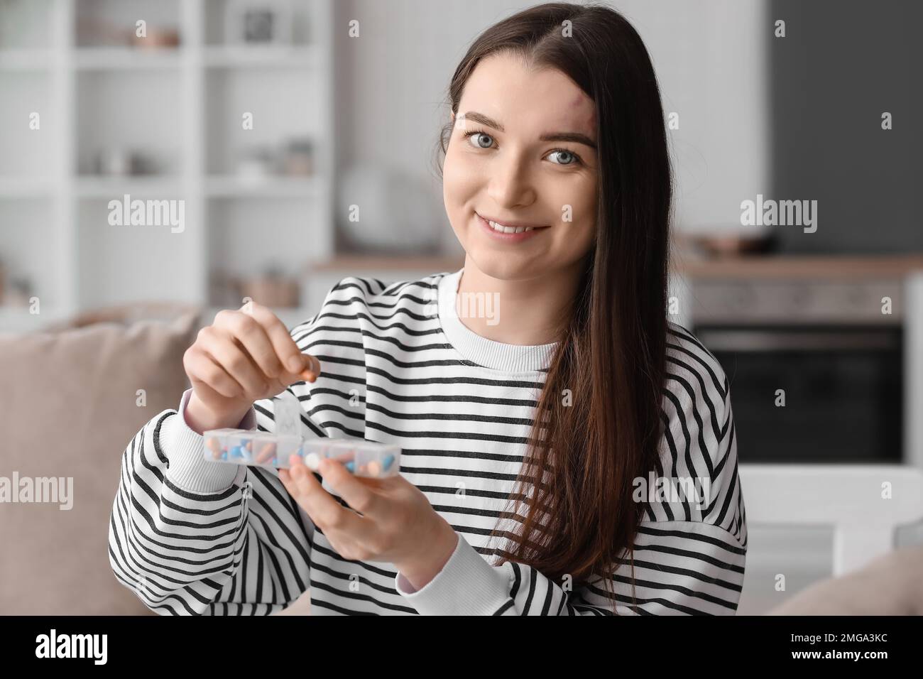 Young woman taking vitamin supplement from container at home Stock ...