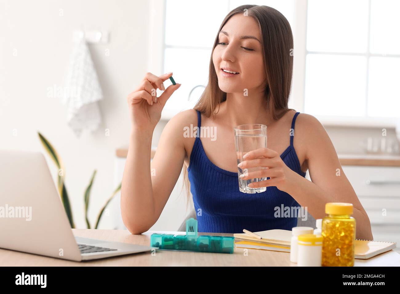Beautiful woman with glass of water taking vitamin supplement in ...