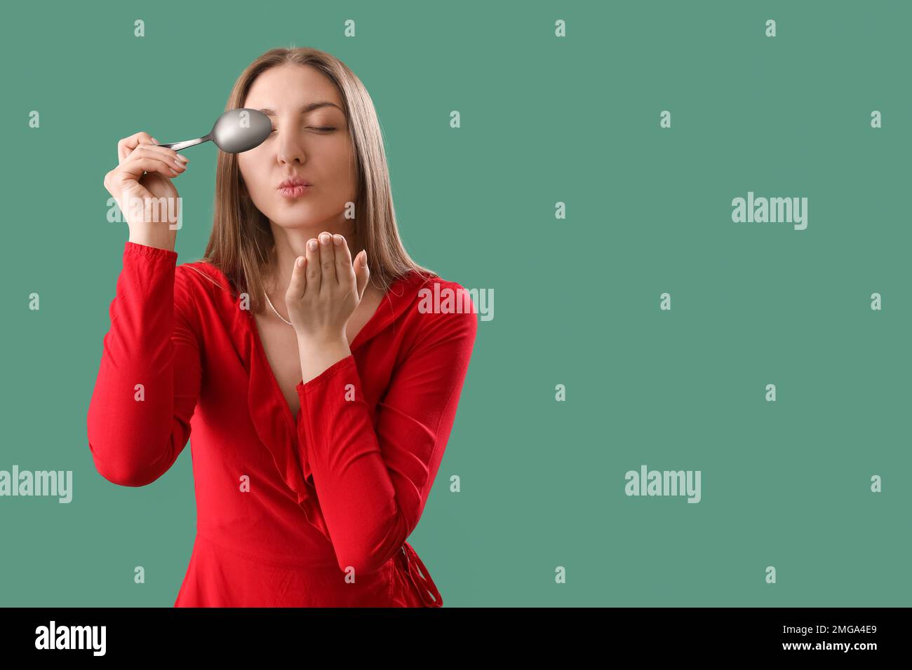 Beautiful woman with spoon blowing kiss on green background Stock Photo ...