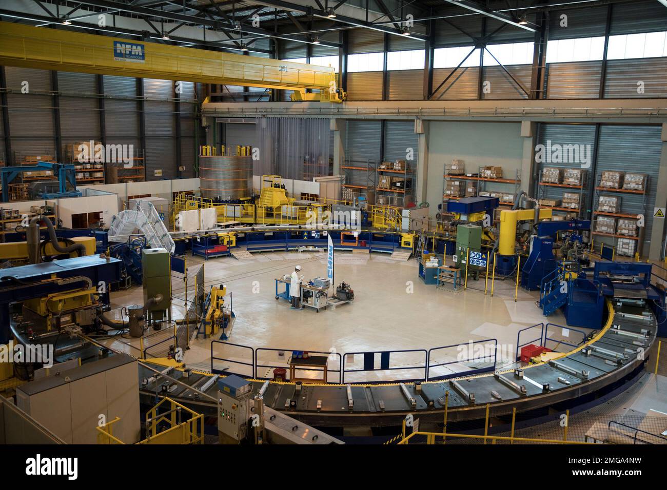 A worker stands in the middle of an ITER poloidal field coil meant for ...