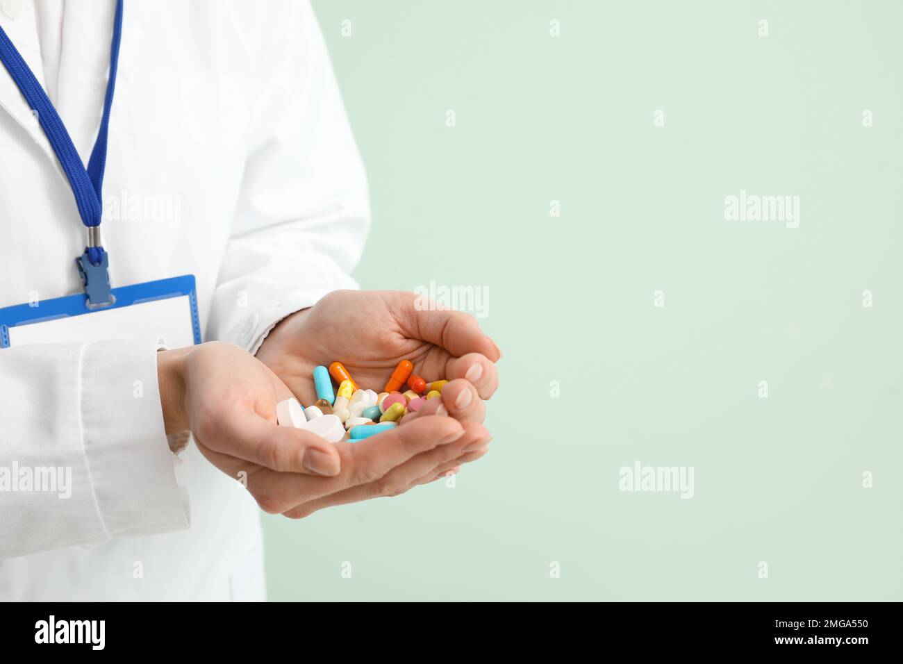 Female doctor with pile of vitamin supplements on green background ...