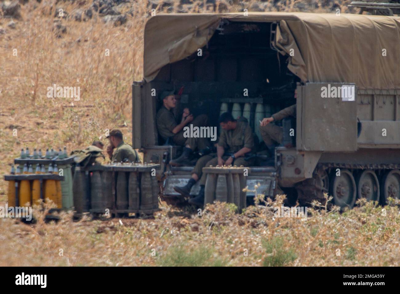 Israeli soldiers sit by shells next to an Israeli mobile artillery unit ...