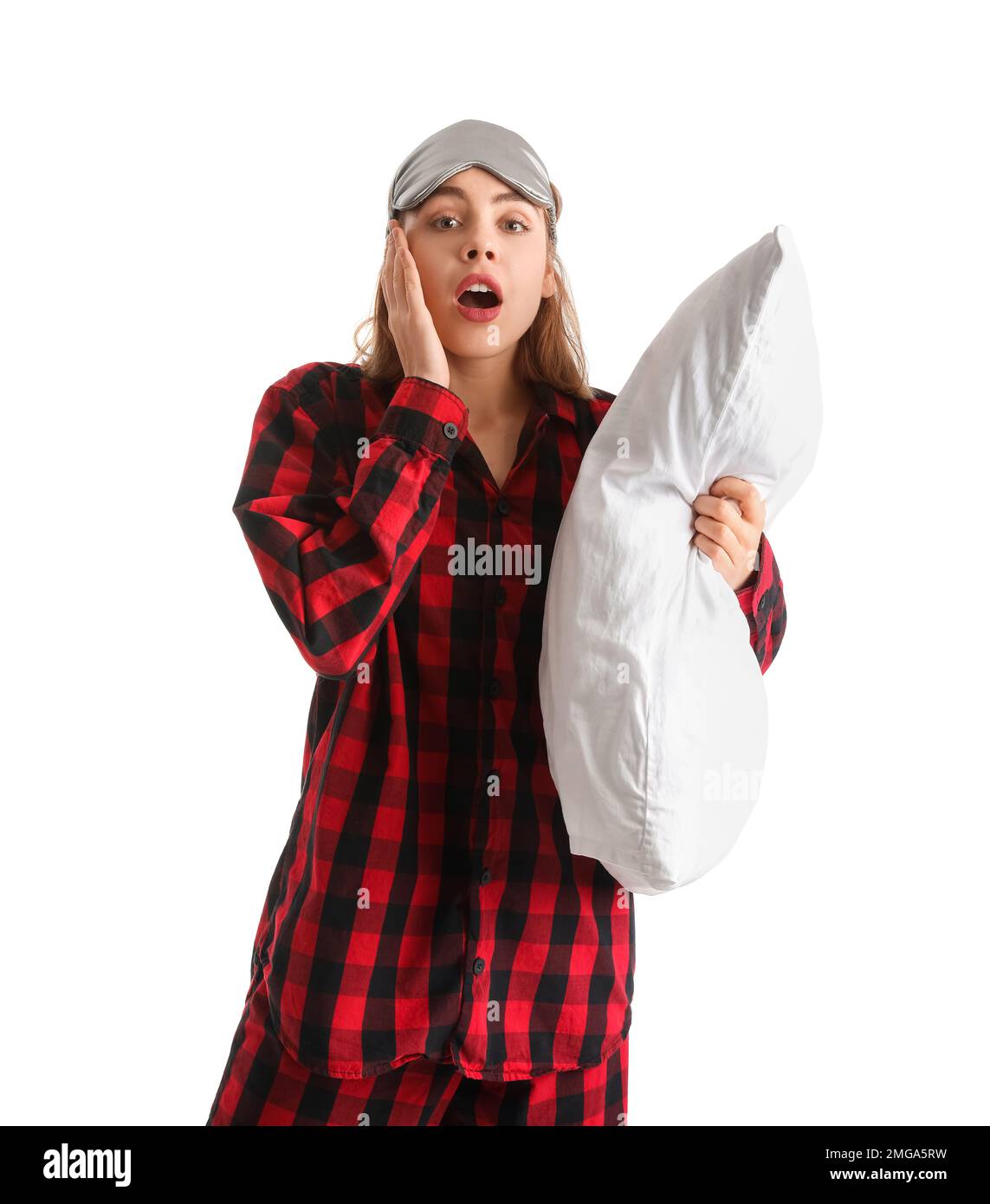 Shocked young woman in checkered pajamas with pillow on white ...