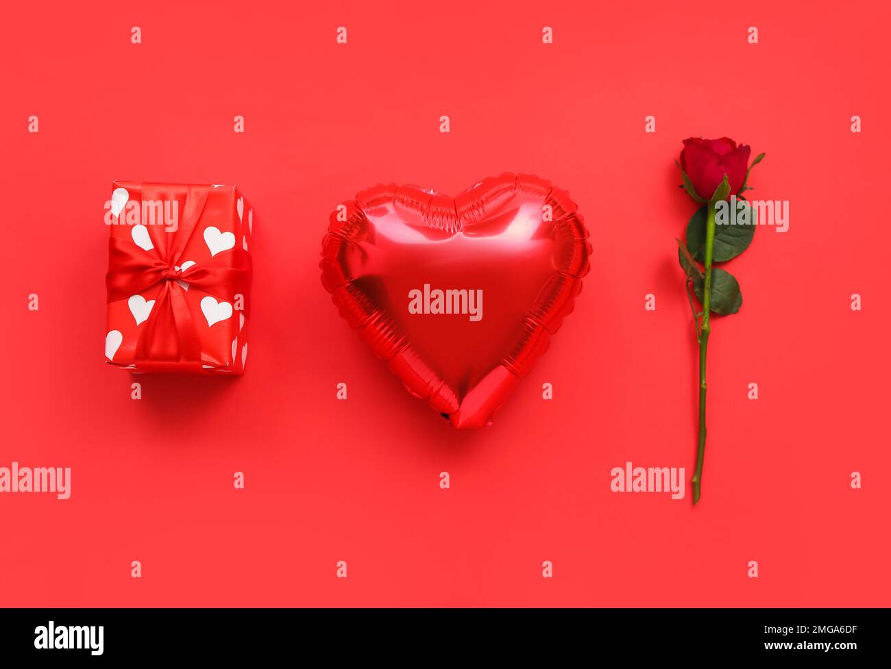 Heart shaped balloon, rose flower and gift box on red background ...