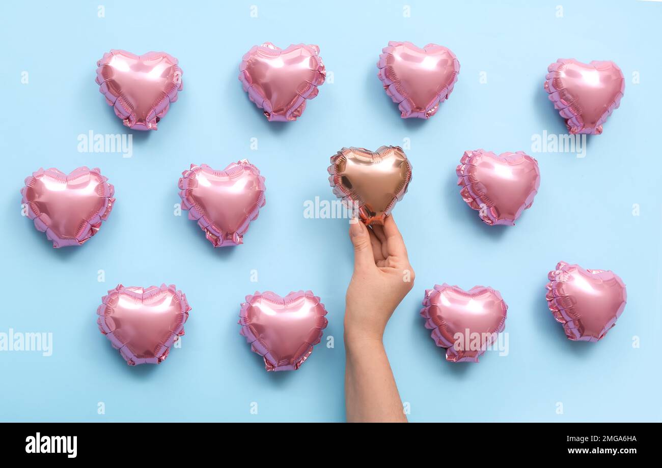 Female hand with beautiful heart shaped balloons on color background ...