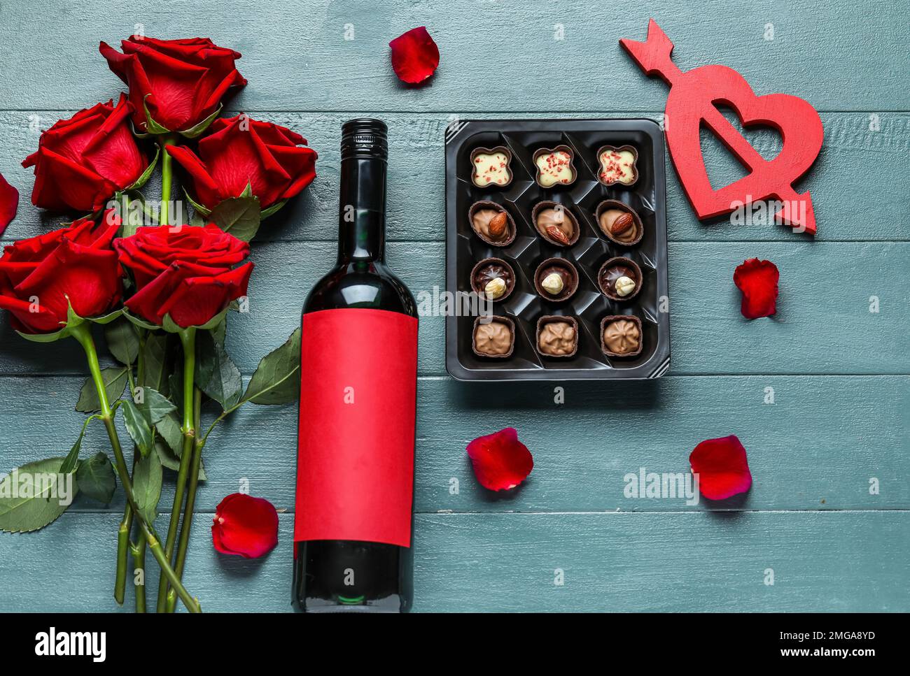 Bottle of wine, box with candies, heart and rose flowers on grey wooden ...