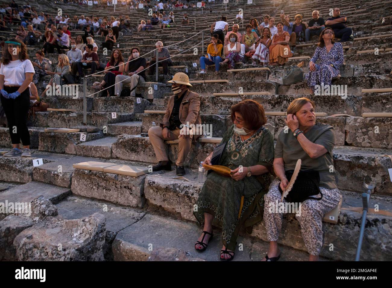 Spectators, some of them wearing protective face masks sit at the ...