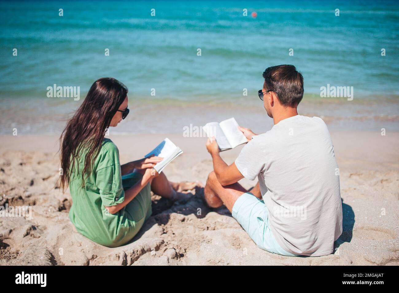Young couple reading books on tropical beach Stock Photo - Alamy