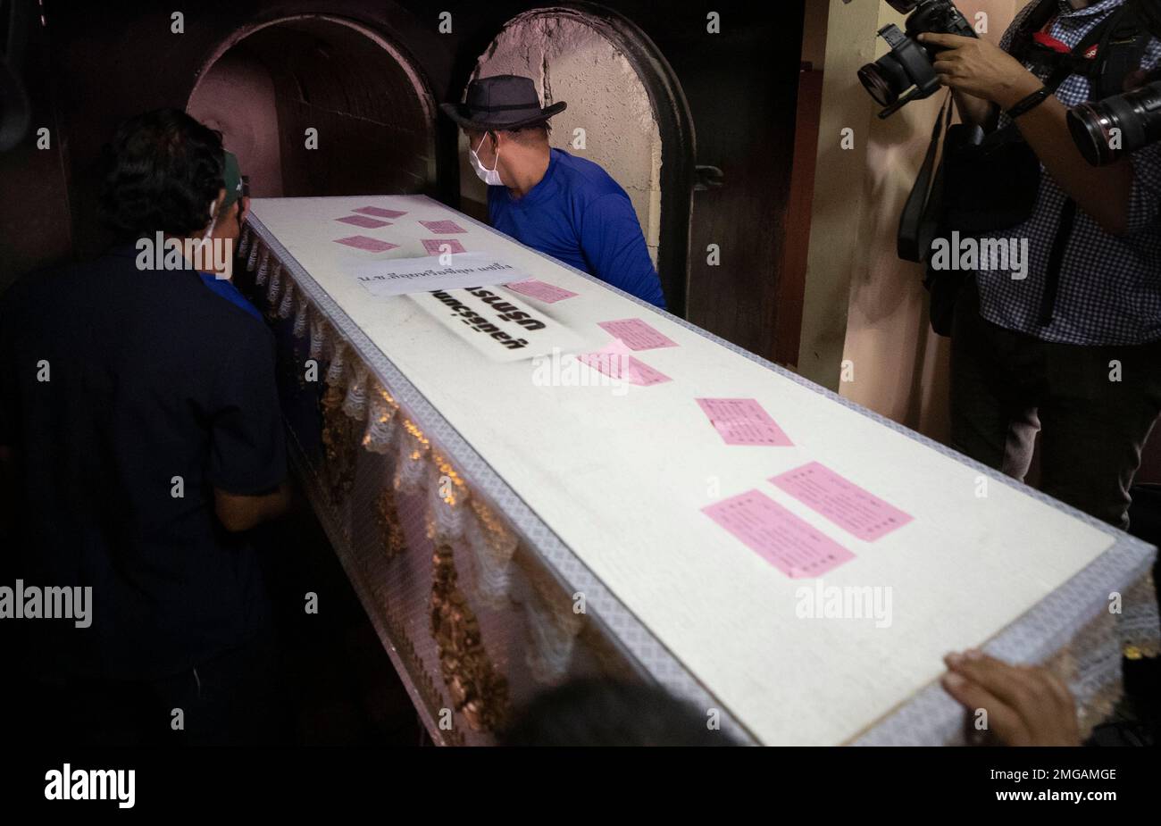 Charity workers put the coffin of Si Ouey into an incinerator for ...