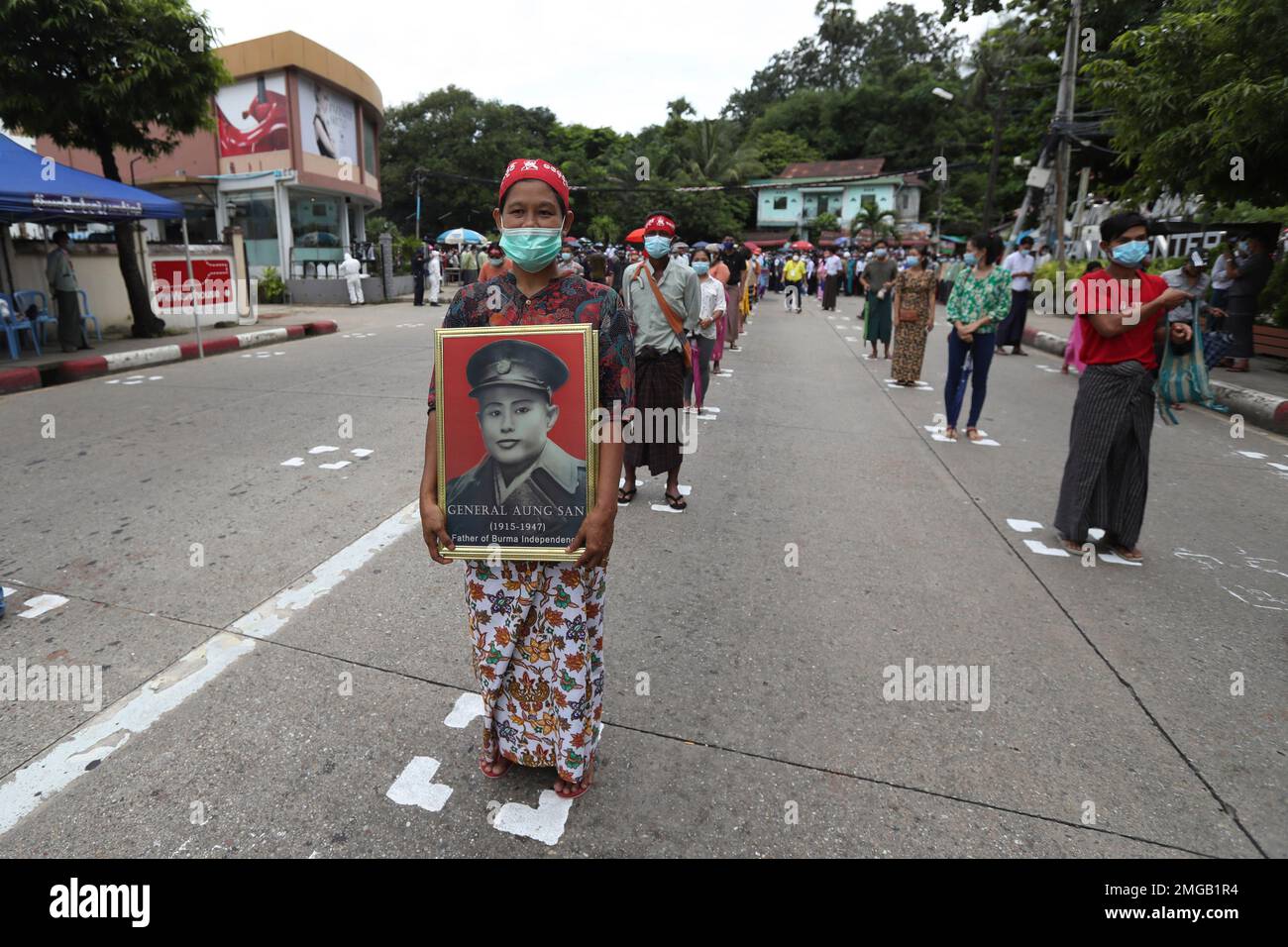 A woman holding a portrait of Gen. Aung San waits to pass a check point ...
