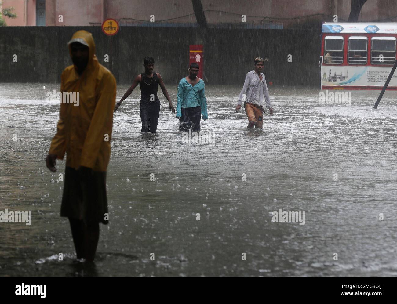 People wade through a waterlogged street during heavy rainfall in ...