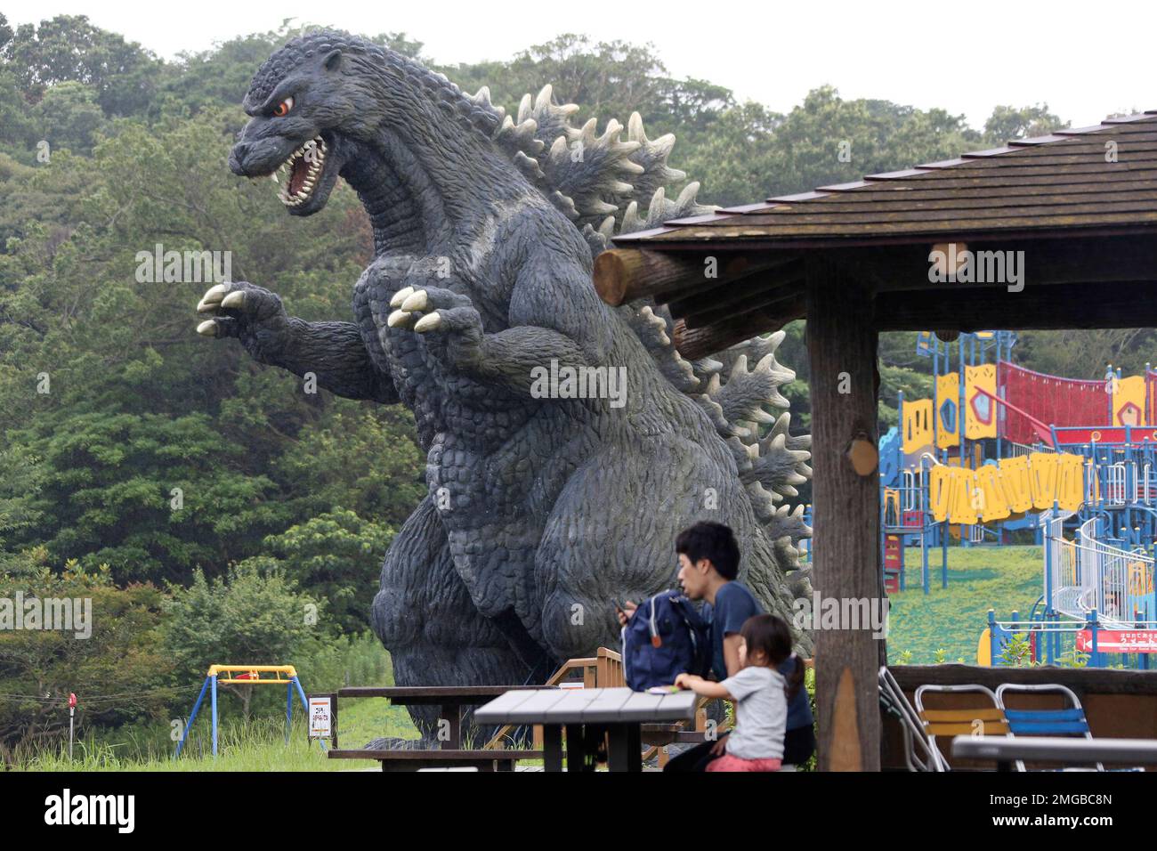 A family sit on a bench near a Godzilla's slide at Kurihama flower park ...