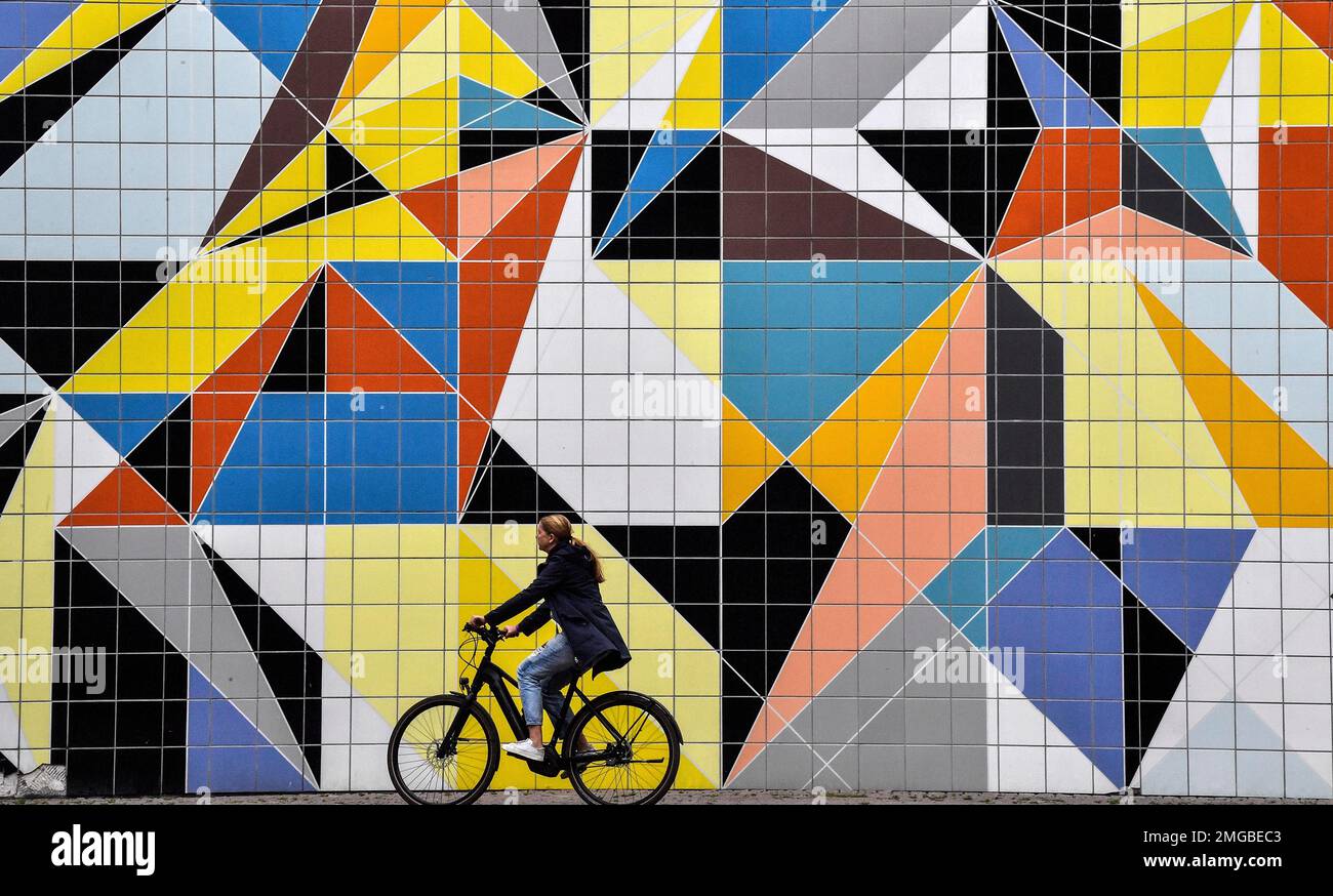 A cyclist passes a colorful tiled mural by American artist Sarah Morris ...