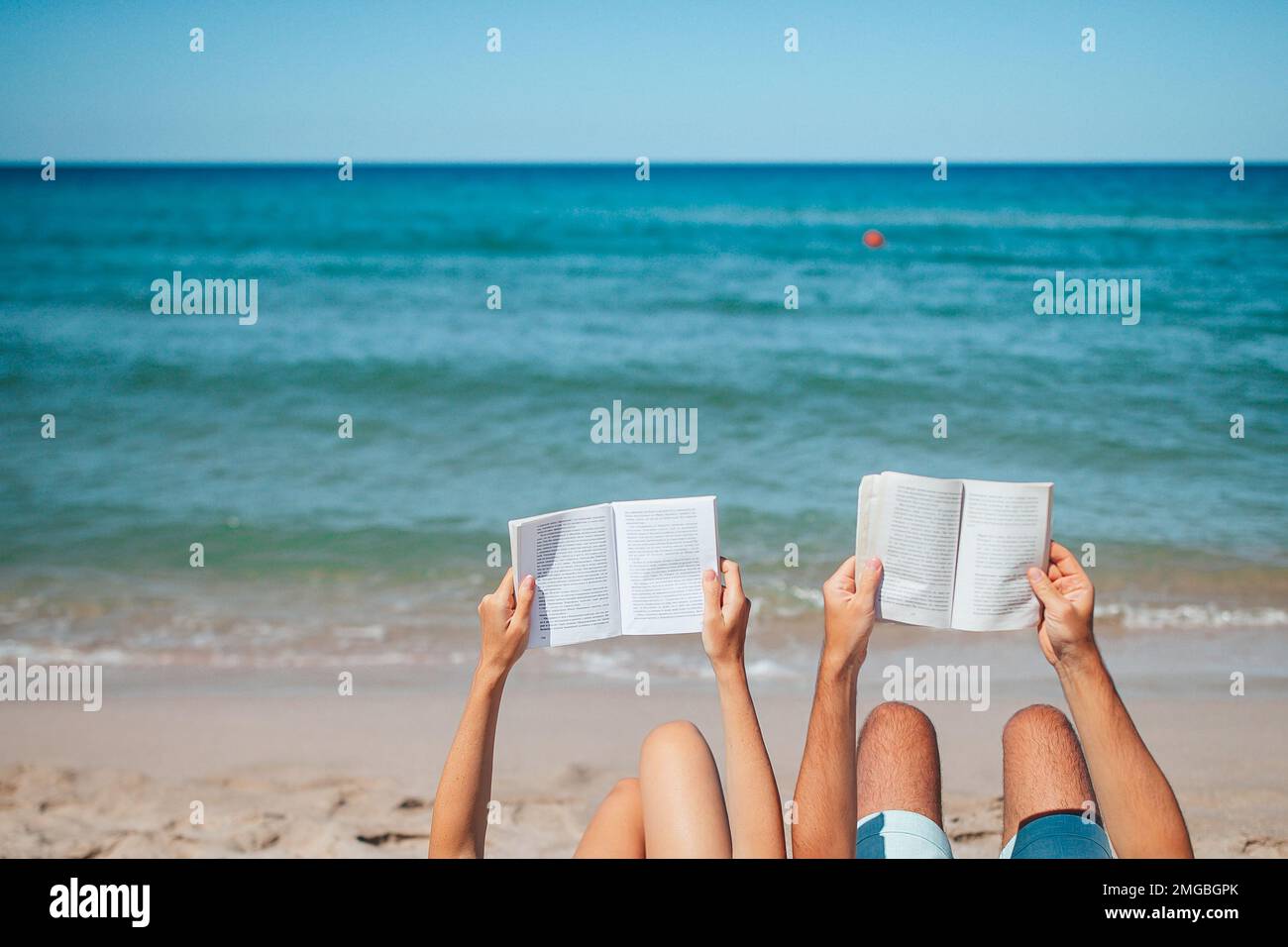 Young couple reading books on tropical beach Stock Photo - Alamy