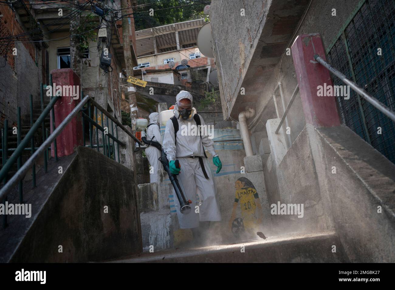 A volunteer sprays disinfectant in an alleyway to help contain the ...