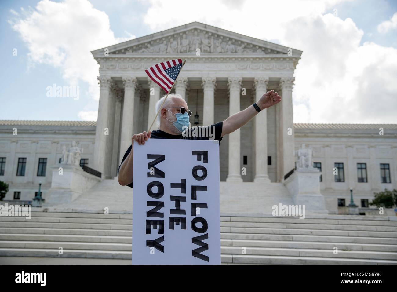 Bill Christeson holds up a sign that reads "Follow the Money" outside ...