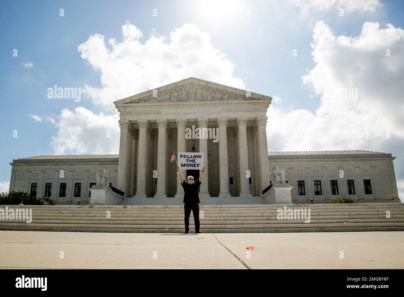 Bill Christeson holds up a sign that reads "Follow the Money" outside ...