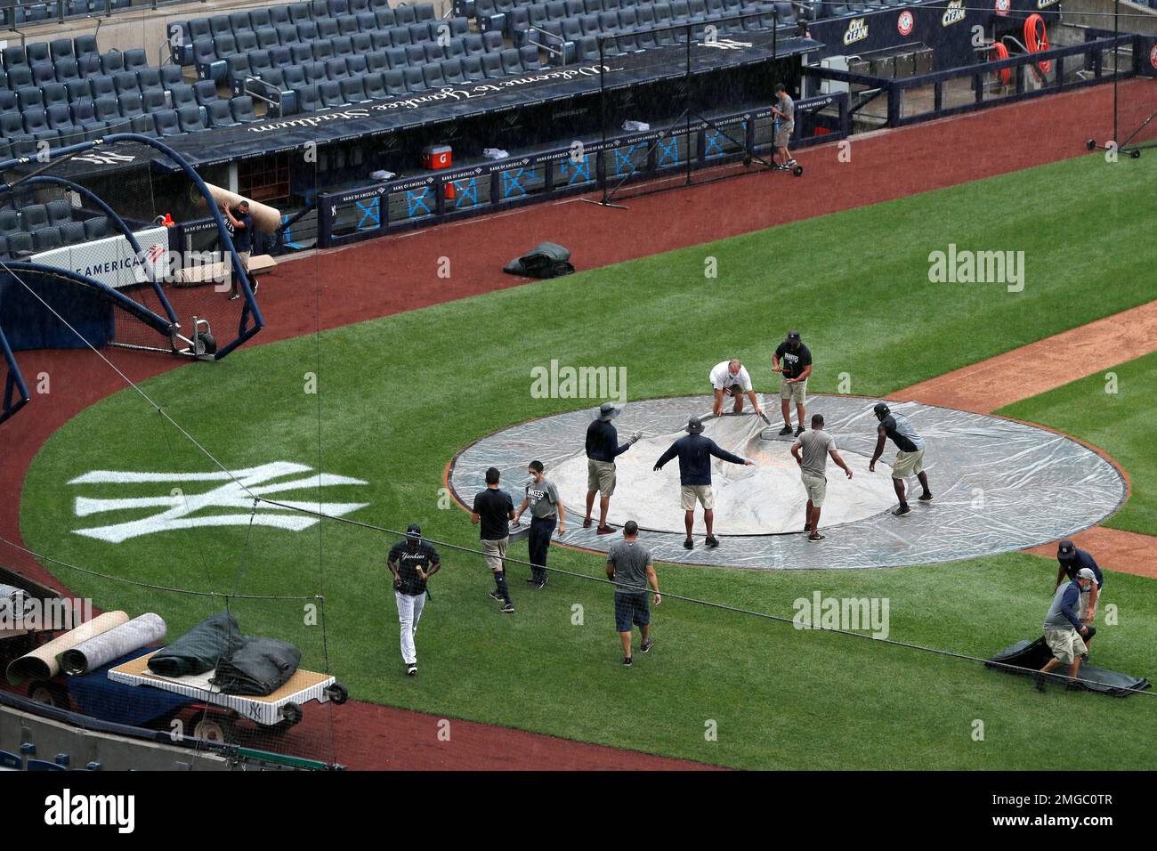 Groundskeepers lay tarps atop home plate as a sudden rainstorm cut ...