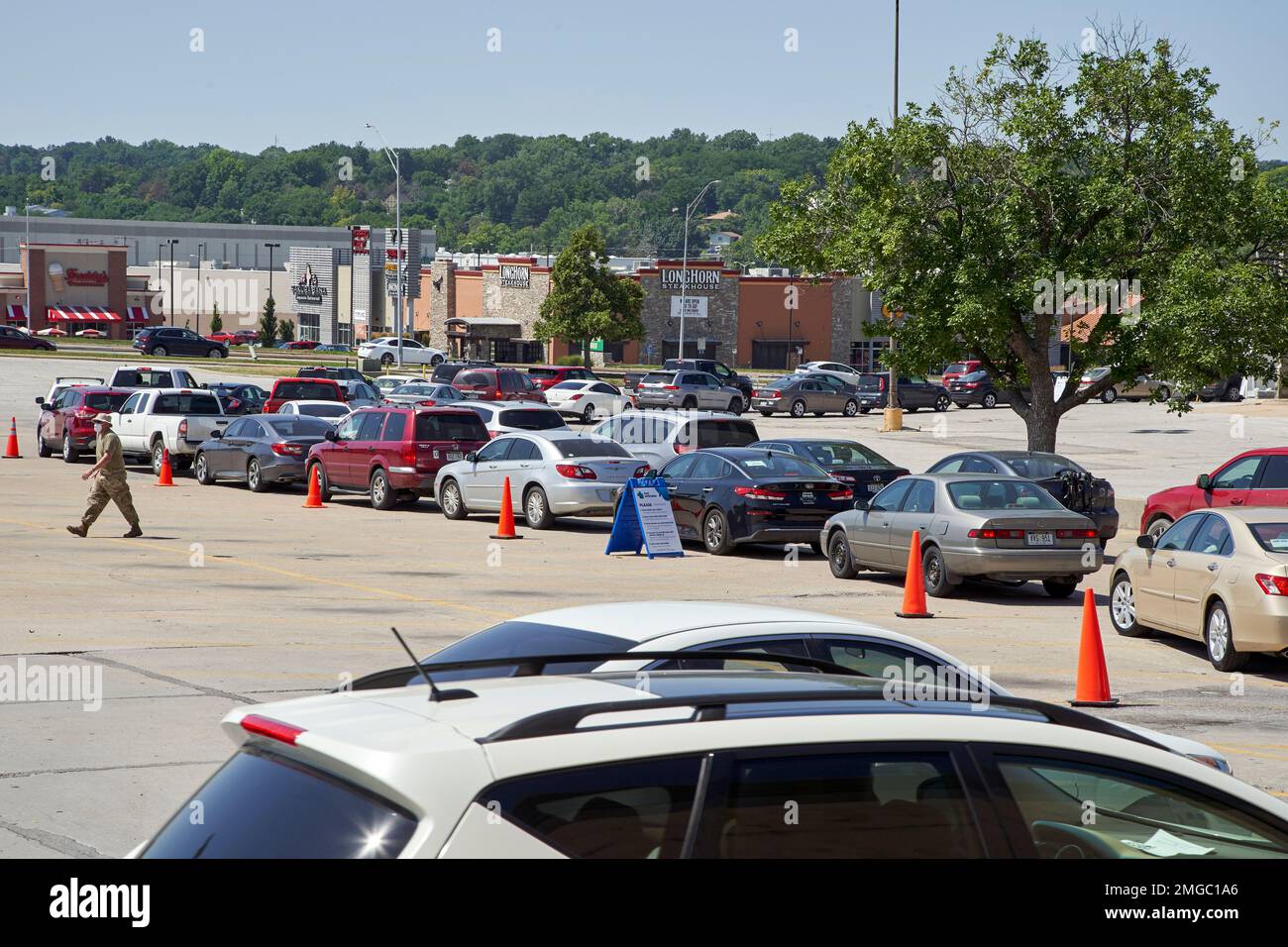 A double line of cars snakes around a parking lot at a coronavirus ...