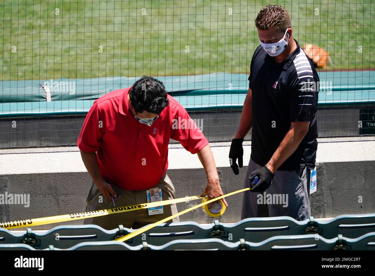 Los Angeles Angels staff members measure and apply caution tape between ...