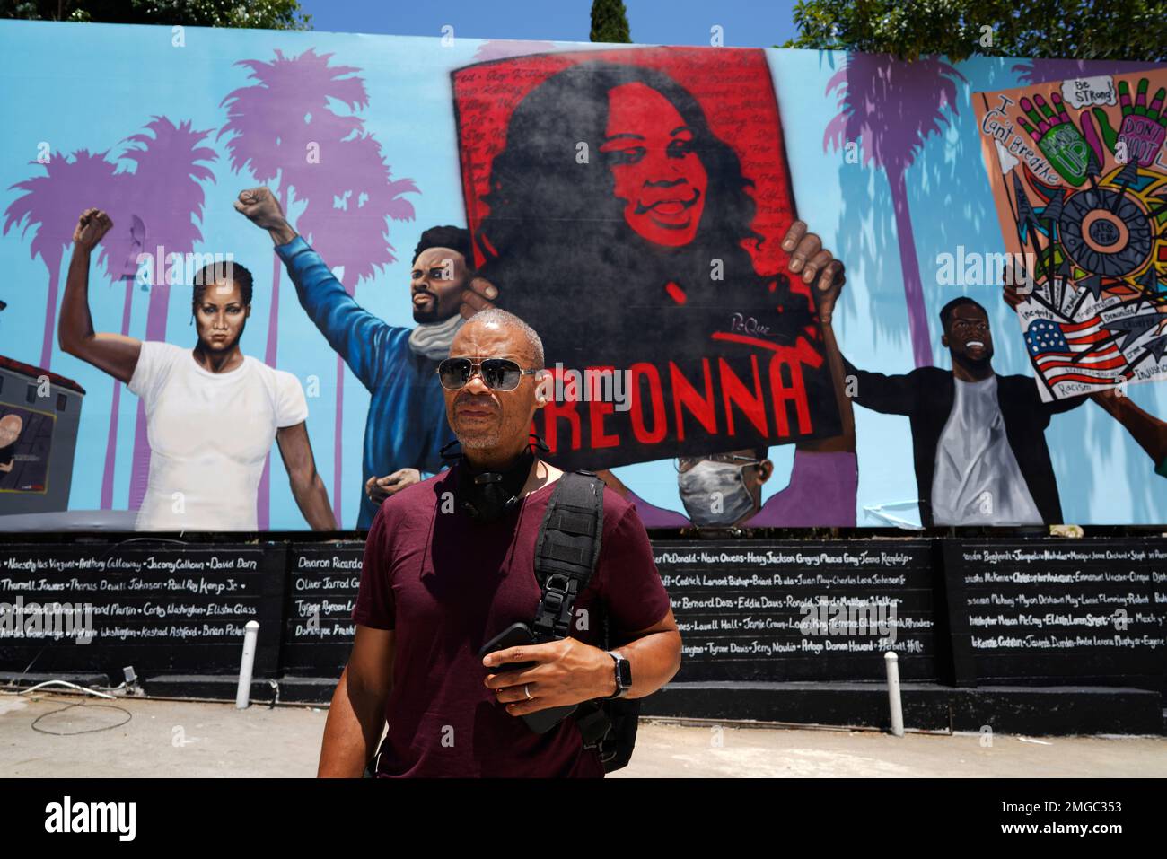 Artist PeQue Brown stands by a section of a mural he painted as part of ...
