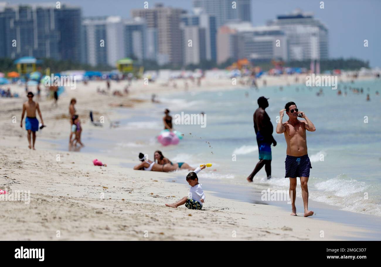 Beach goers walk along the shore on Miami Beach, Florida's famed South ...