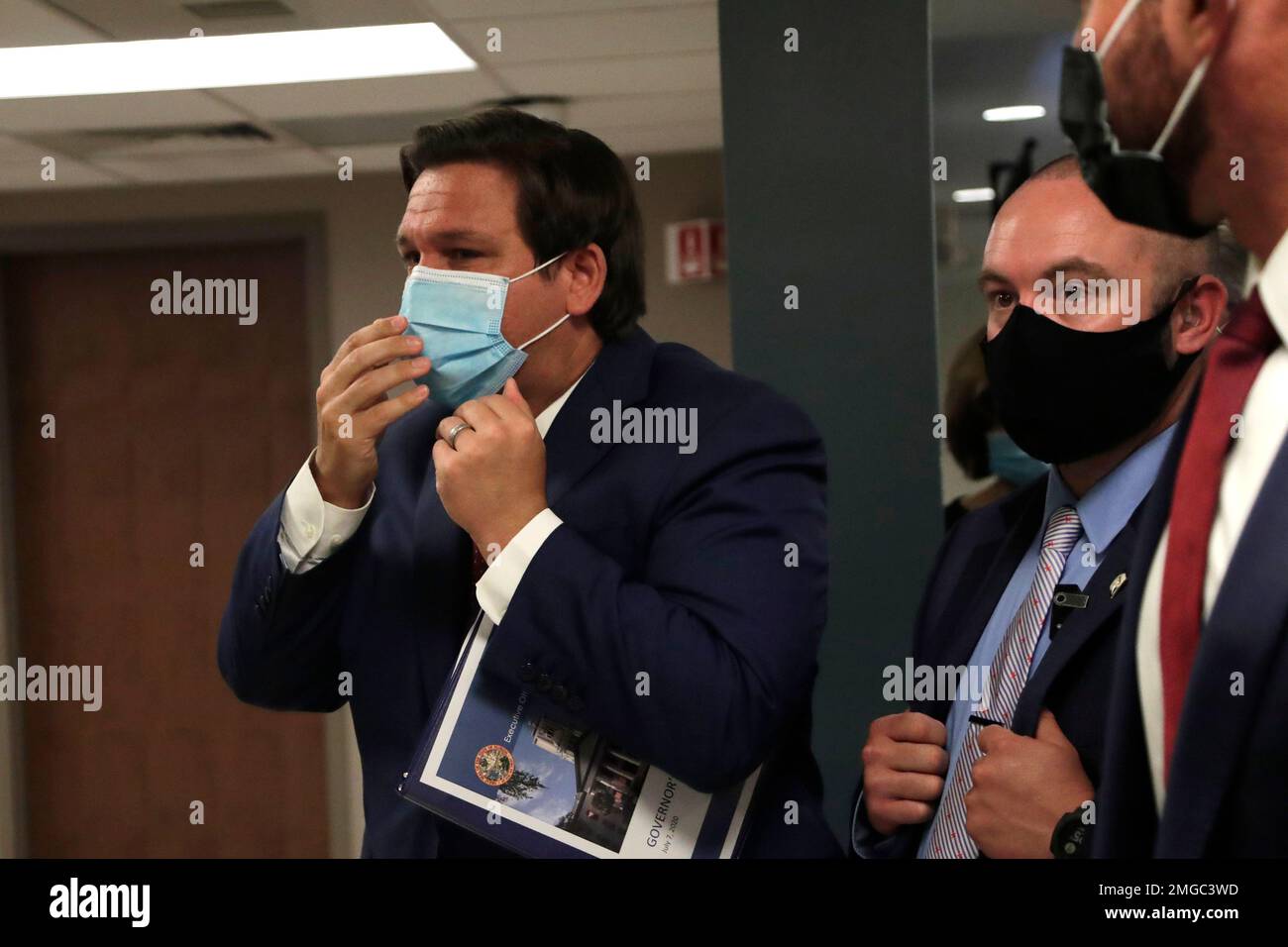 Florida Gov. Ron DeSantis, left, adjusts his face mask as he leaves a ...