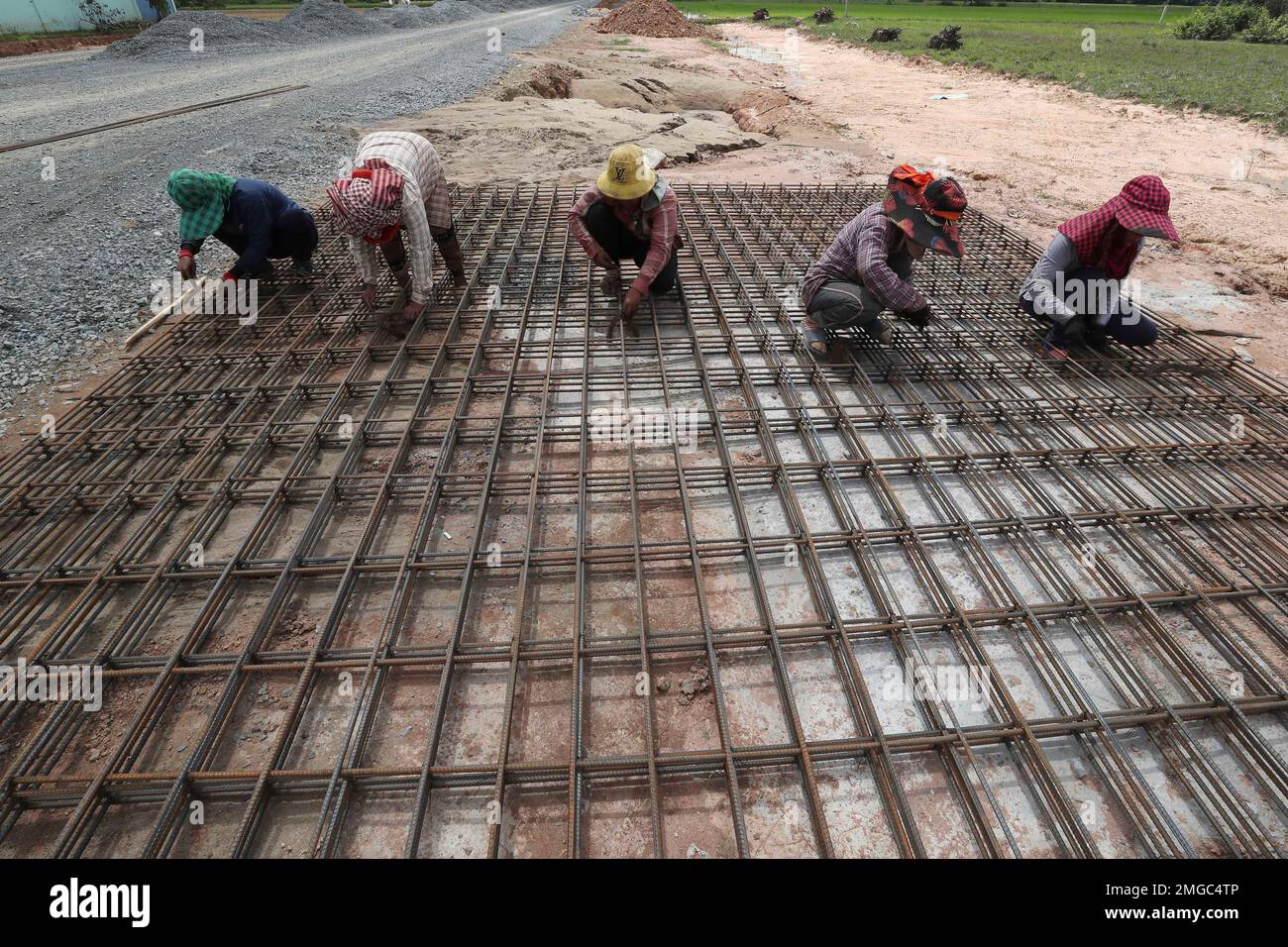Construction workers tie rebar before laying cement for a new road ...