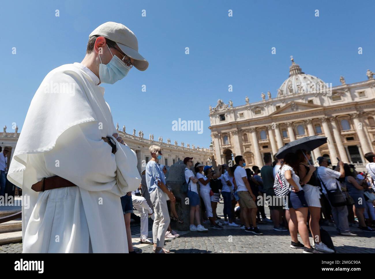 A friar wearing a protective mask prays during the Angelus prayer ...