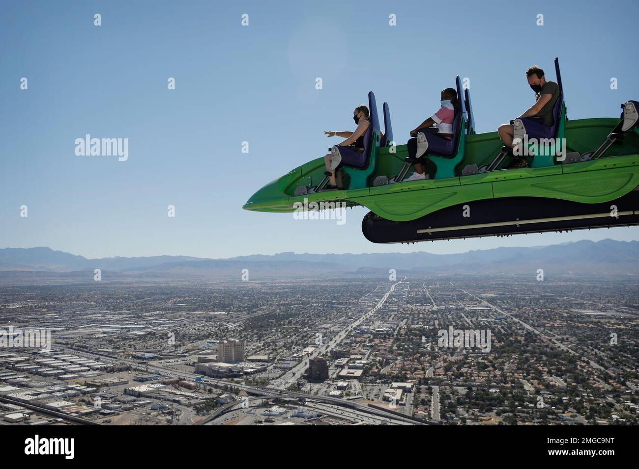 People in masks ride a thrill ride above the Las Vegas Strip on the ...