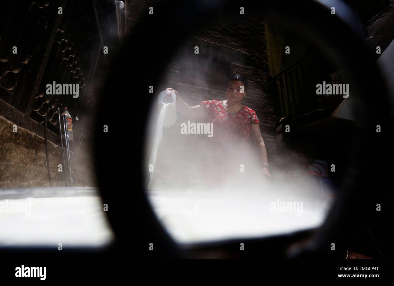 A traditional Nepalese yogurt maker boils milk to prepare yogurt during ...