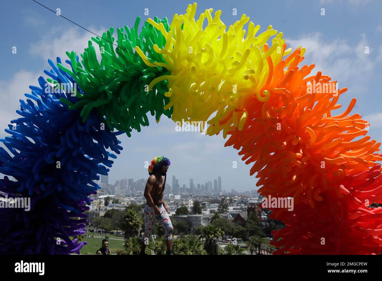 A man walks behind a rainbow of balloons set up by Ronnie Alvarez, lead ...