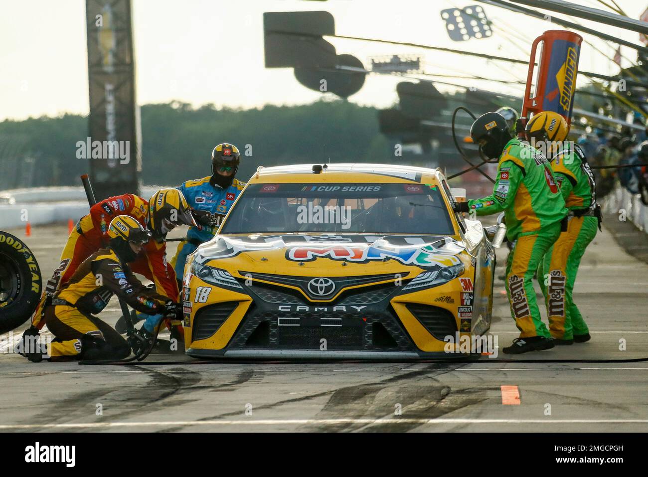 Crew members for Kyle Busch scramble around the car in a pit stop ...