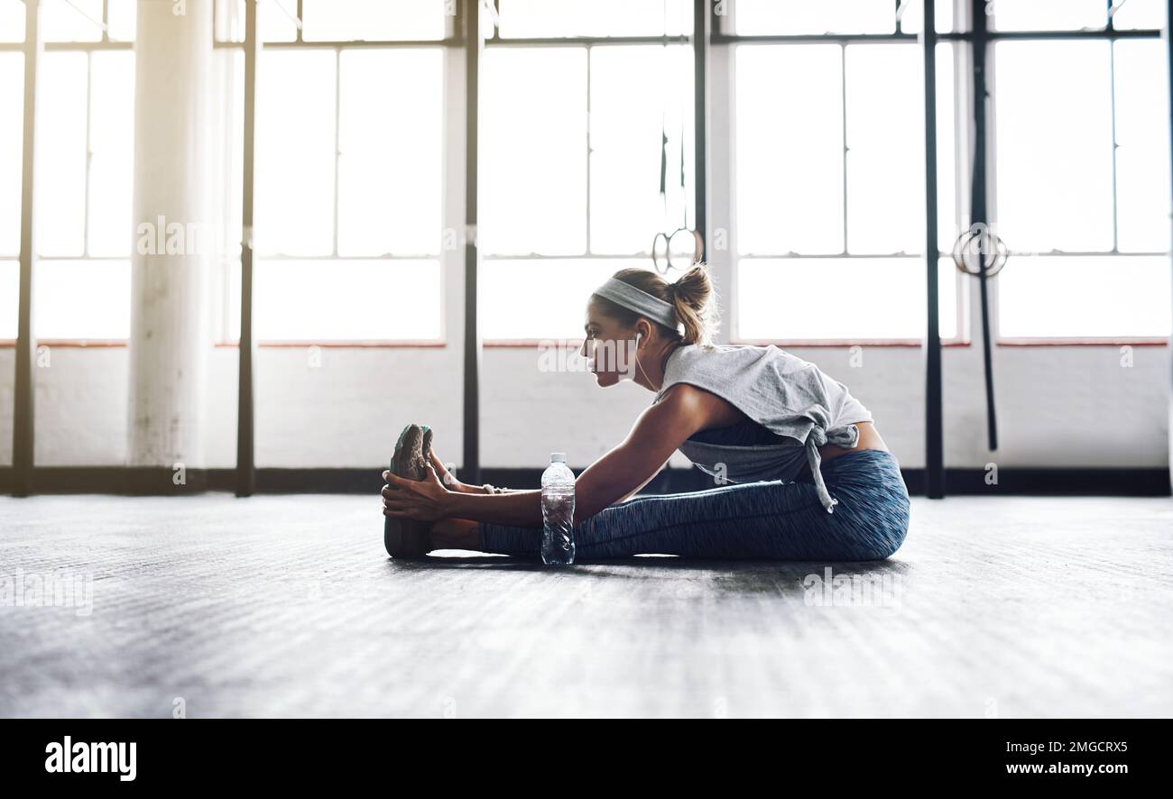 Im working on myself by myself. an attractive young woman stretching at ...