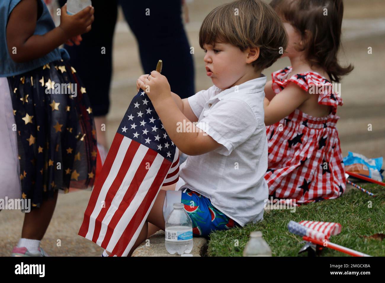 Sam Maddox, 2, works carefully at untangling his American flag during a ...