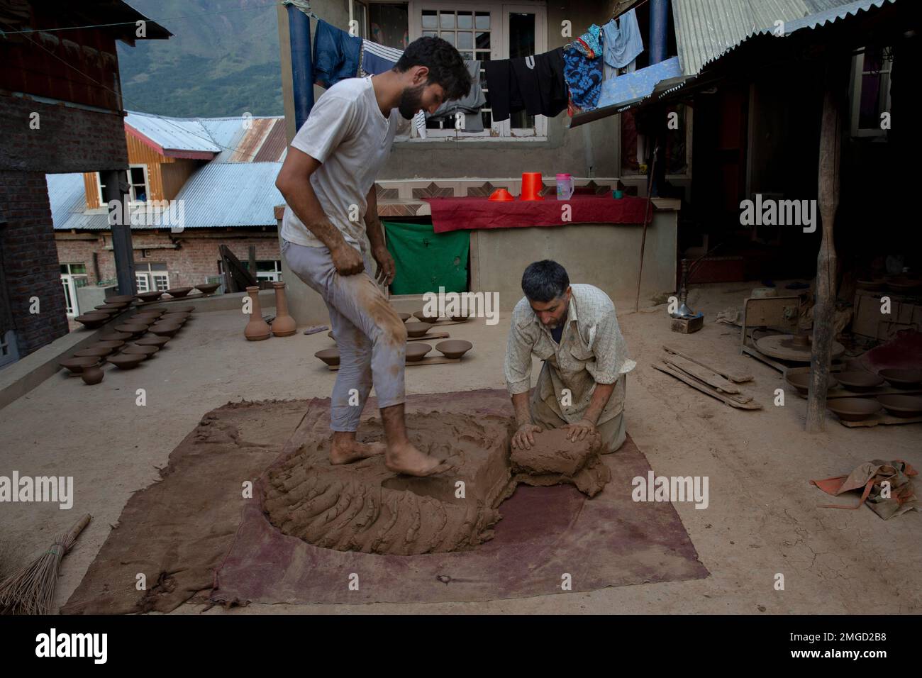 Kashmiri potters Abdul Majeed, right, and his son Mudasir Majeed mixes clay at a workshop ...