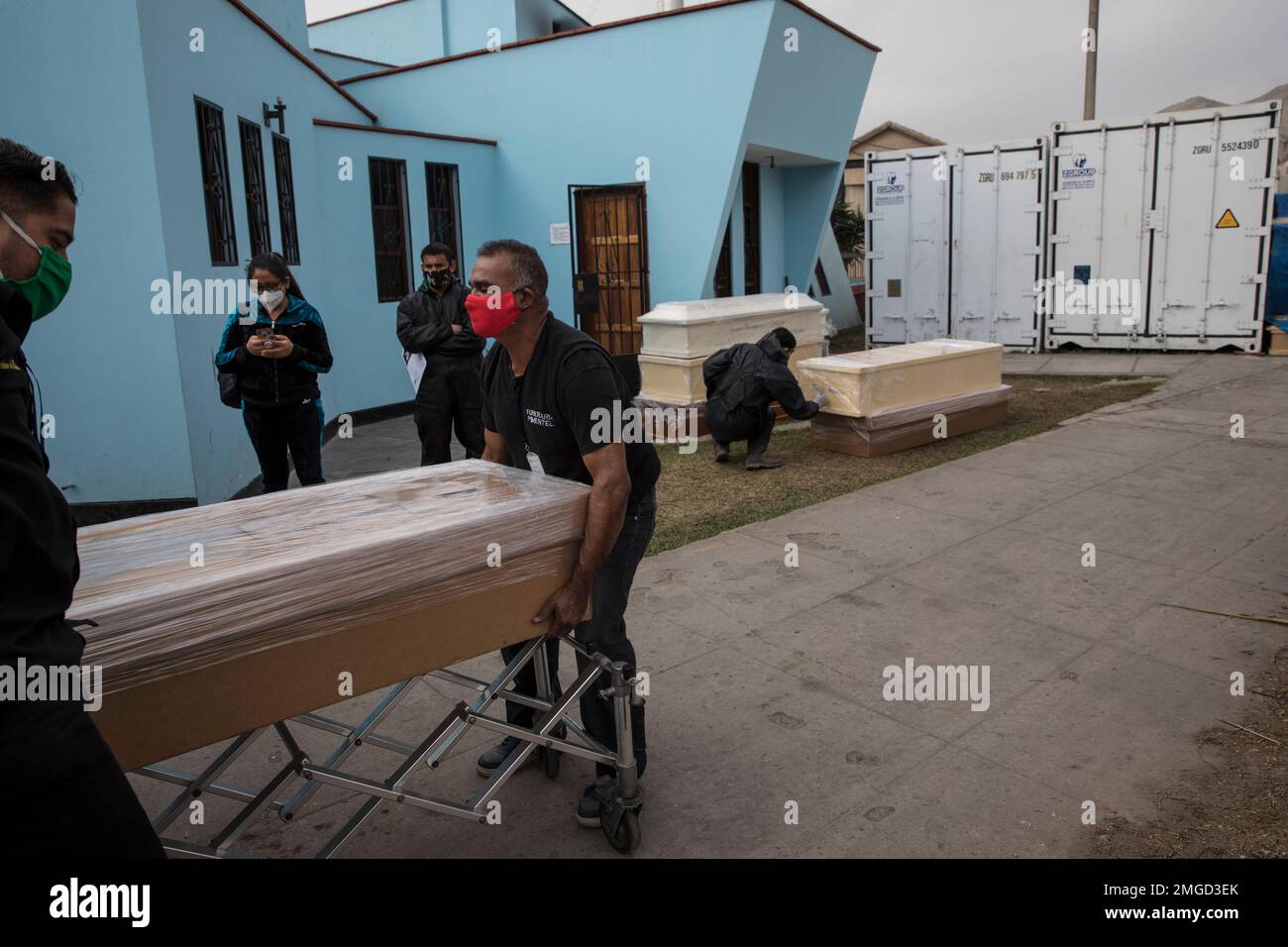 Funeral workers move a coffin containing the corpse of a person who ...