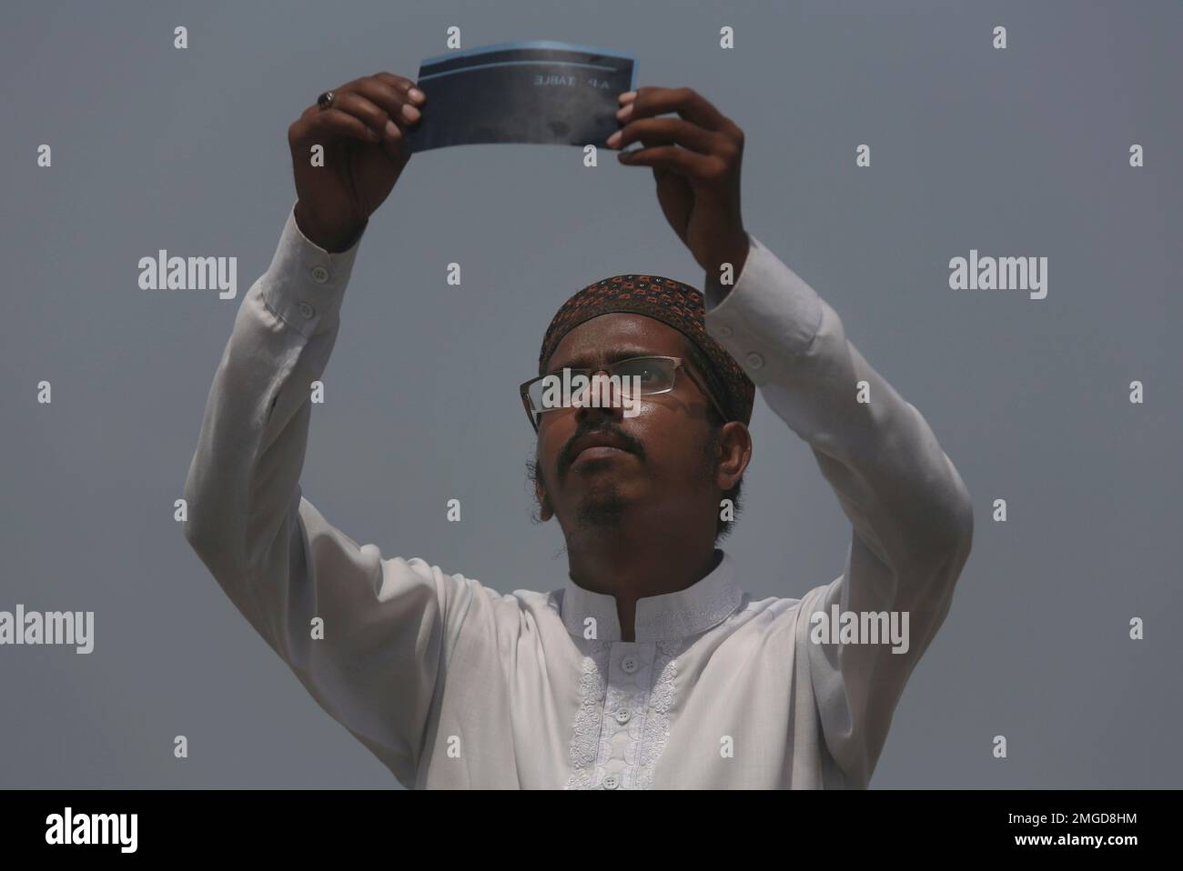 A Pakistani holds x-ray sheet to observe the partial solar eclipse at ...