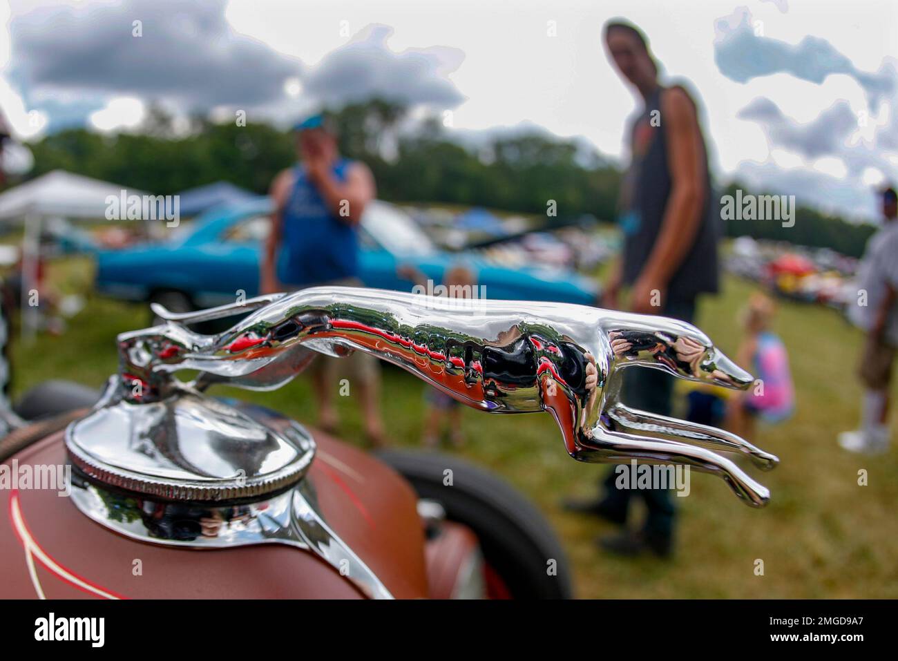 Visitors walk behind the greyhound hood ornament on a 1932 Ford ...