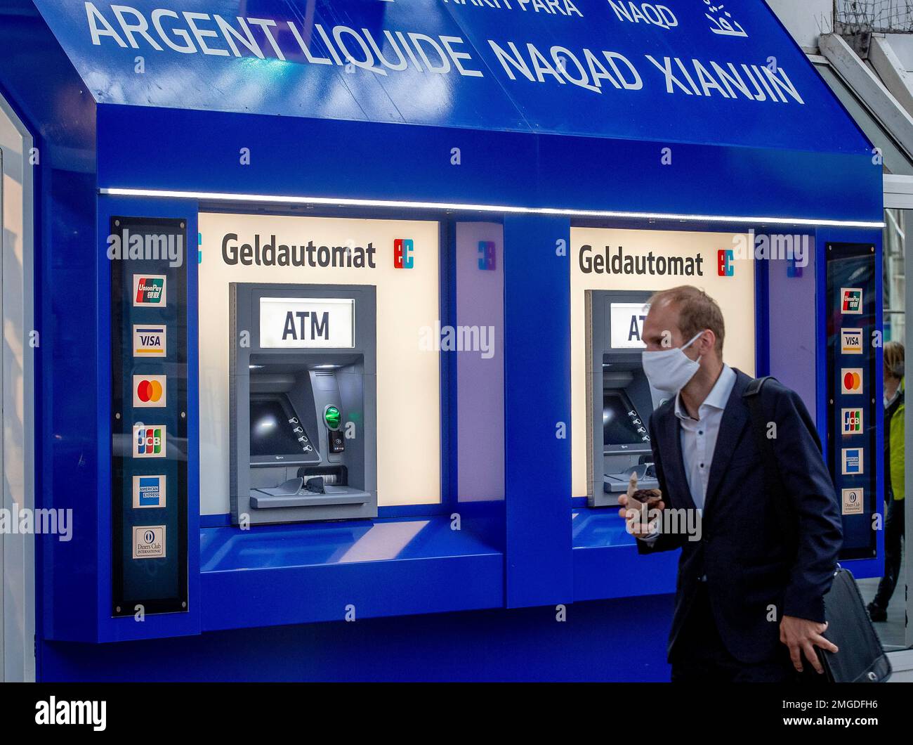 A man passes a banking machine in the central train station in ...
