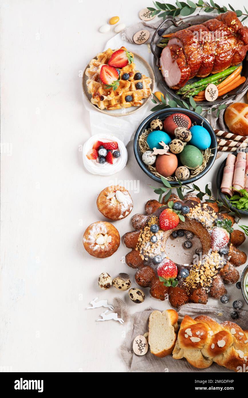 Traditional Easter dinner or brunch with ham, colored eggs, hot cross ...