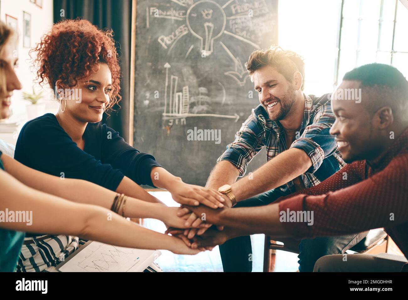 Lets give it our all. a group of designers joining their hands together in a huddle Stock Photo ...