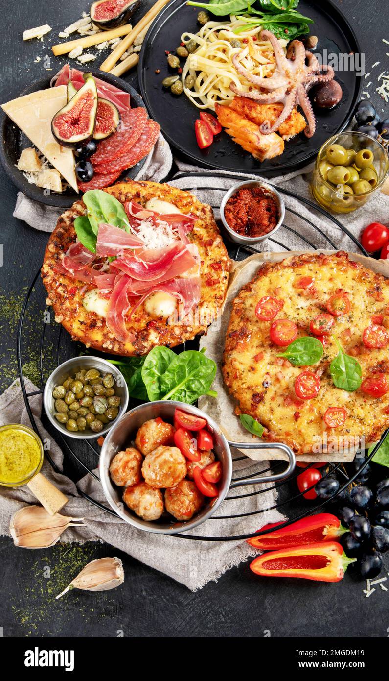 Dinner table of italian meals dishes. Pizza, pasta, antipasto on black ...