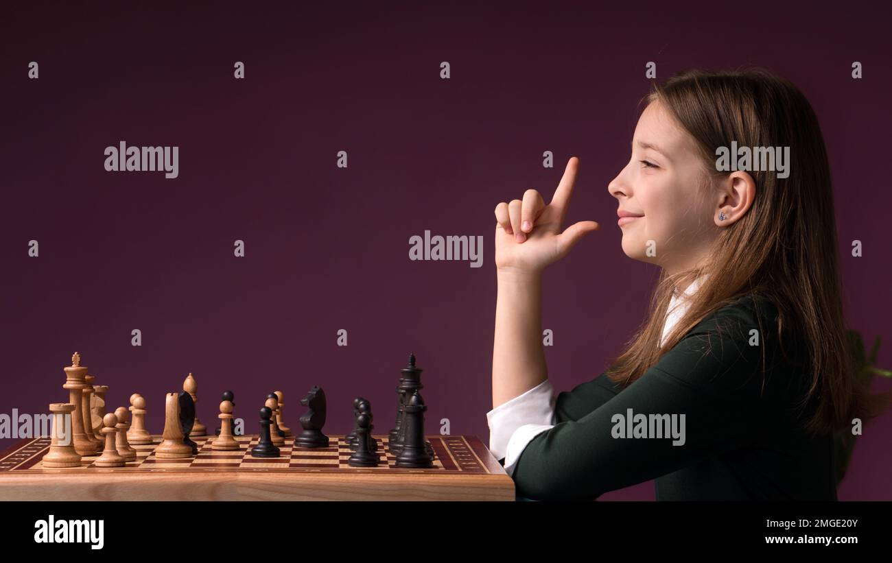 Teen girl playing chess. Young chess player raised index finger and ...