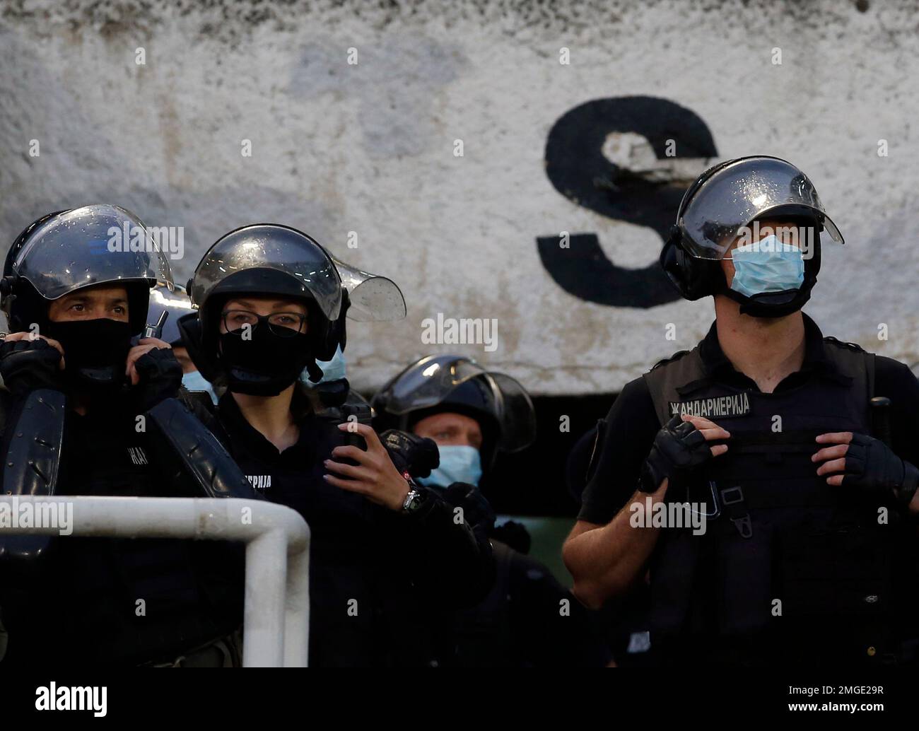 Serbian riot police officers wearing protective face masks watch a ...