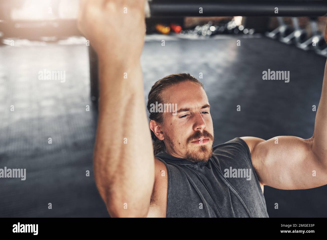 Get a firm grip on your goals. a young man doing pull ups in a gym ...