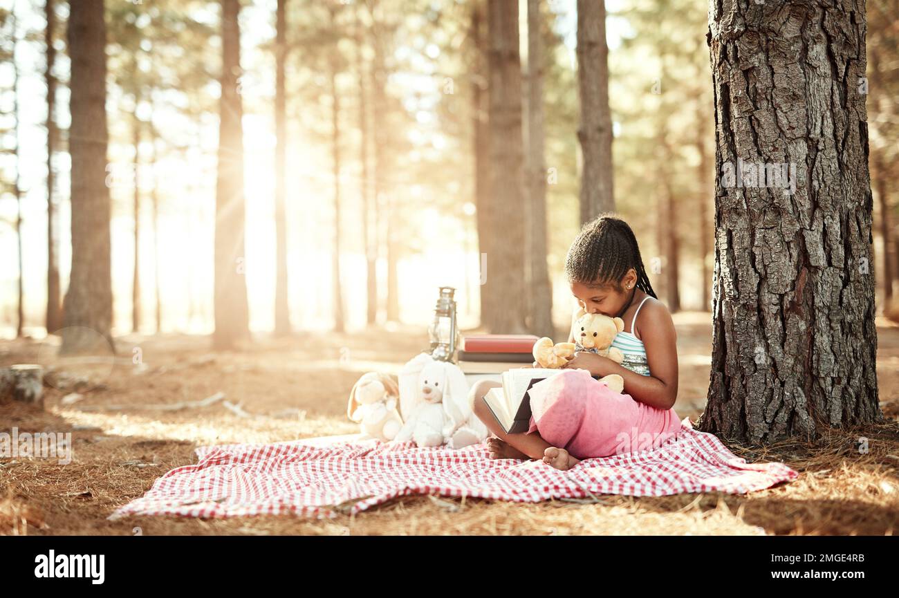Spot the bookworm in the woods. a little girl reading a book with her ...